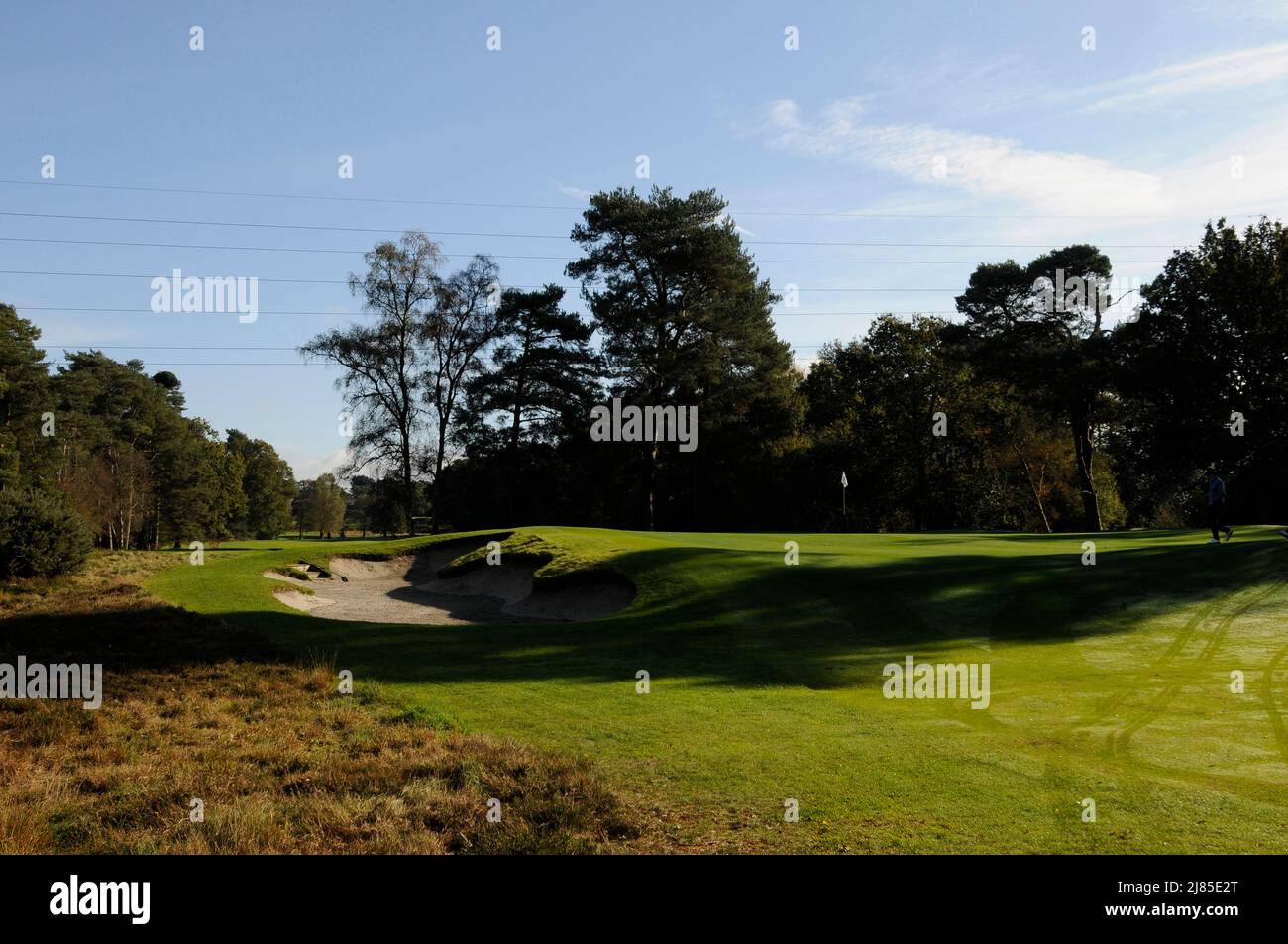 View over heather to 12th Green with small Bunker to left and shadows ...