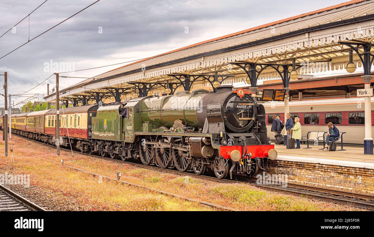 Old steam train arrives at a historic railway station platform. Period ...