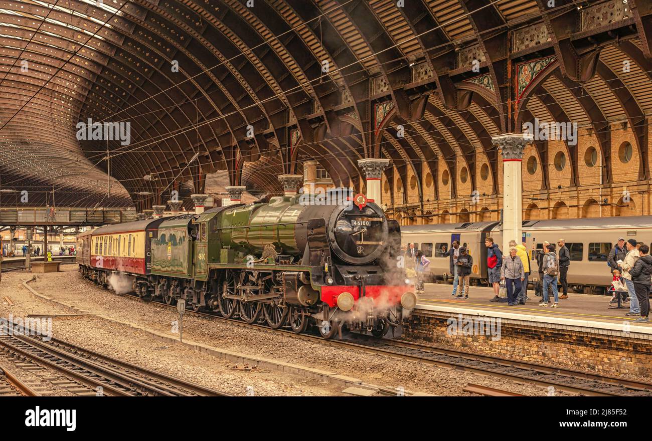 Old steam train stands at a historic railway station platform. Period ...