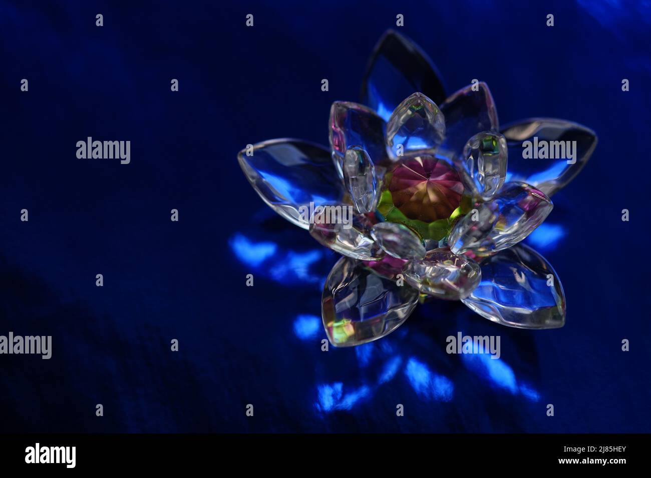 Crystal lotus on rich dark blue shiny table with light reflection ...