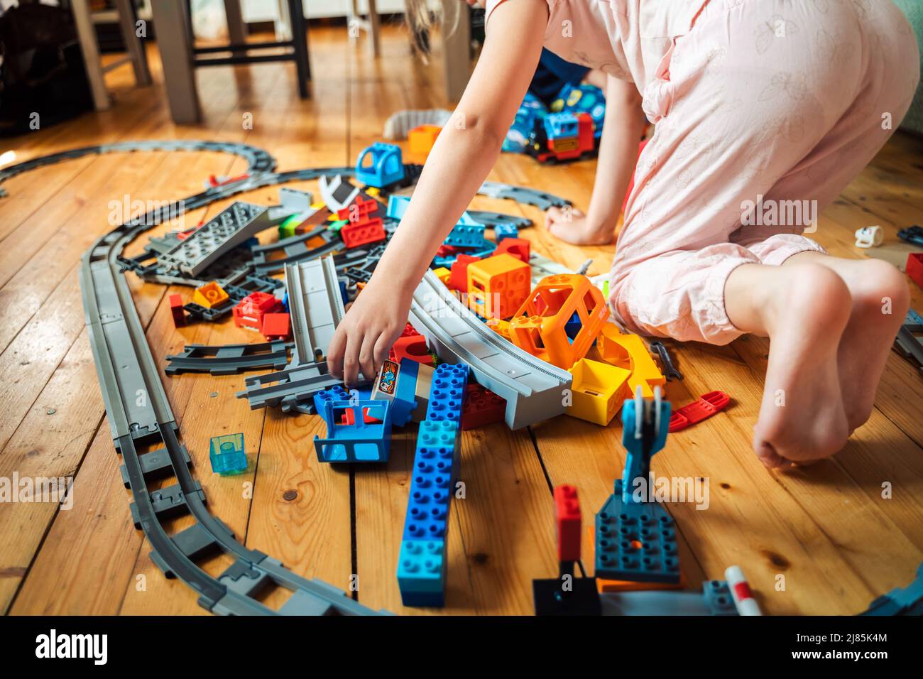 Girls, sisters play kids constructor, build toy railway, railroad by ...