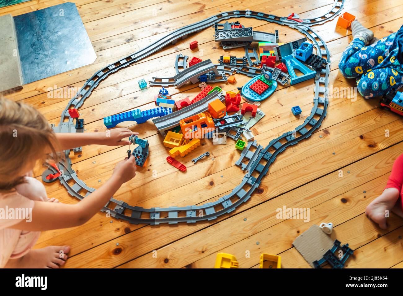 Girls, sisters play kids constructor, build toy railway, railroad by ...