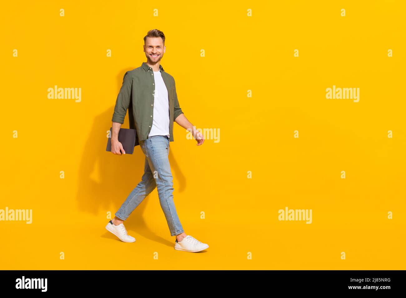 Full length body size view of attractive cheerful guy holding laptop ...