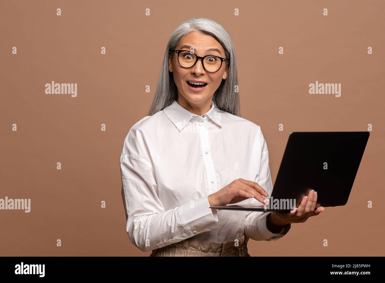 Portrait of smiling worker, happy woman in formal shirt holding laptop, using computer for job ...