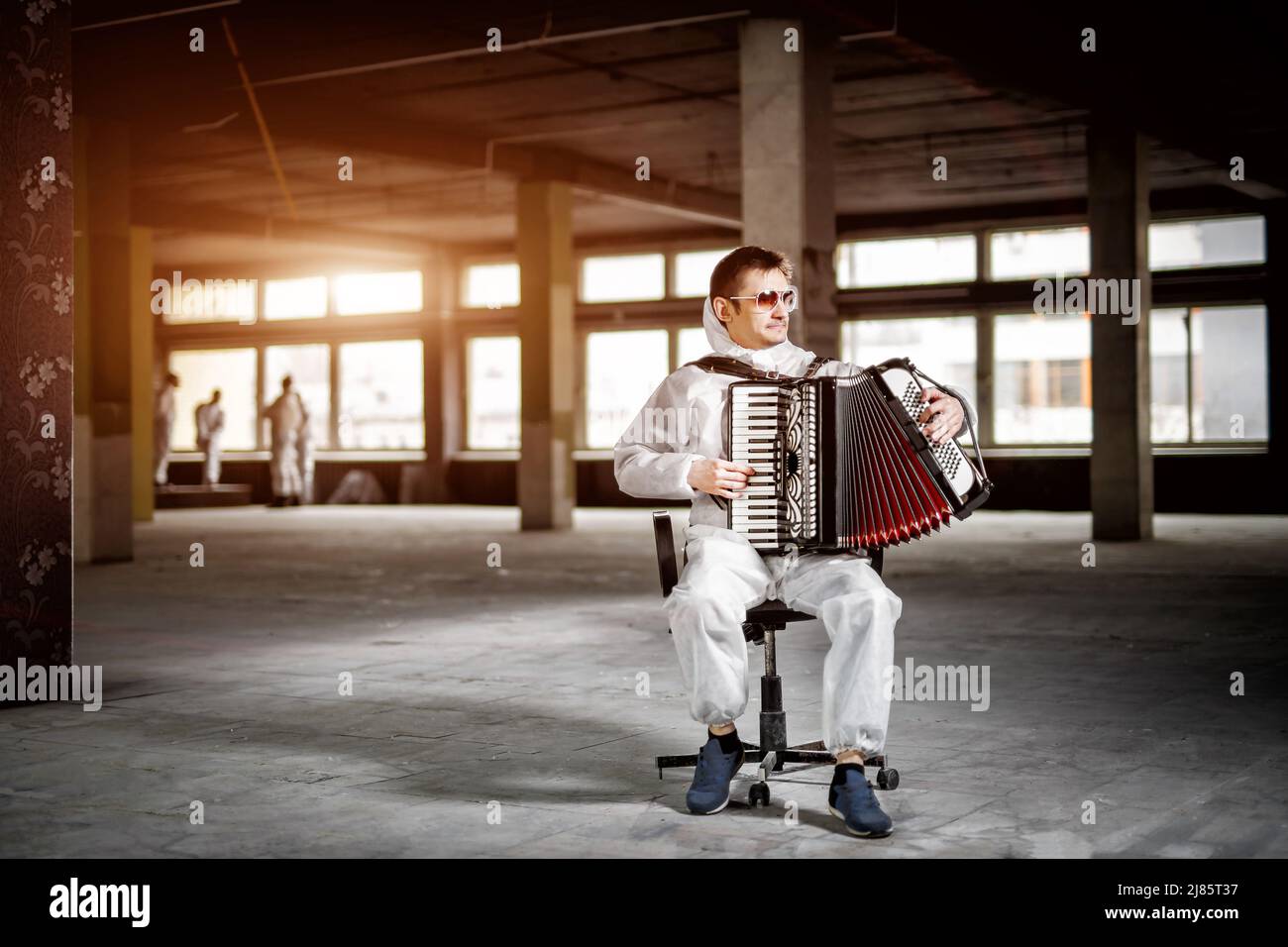 The musician playing the harmonica, accordion in the hall with columns ...