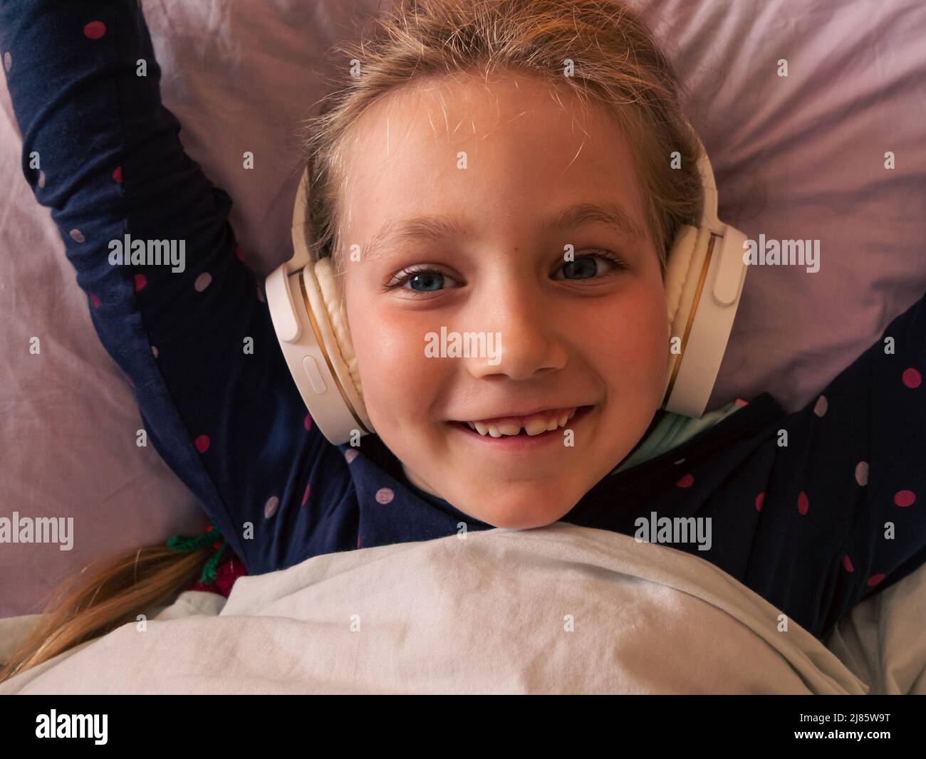 Blonde child girl in headphones learning language listening to music ...