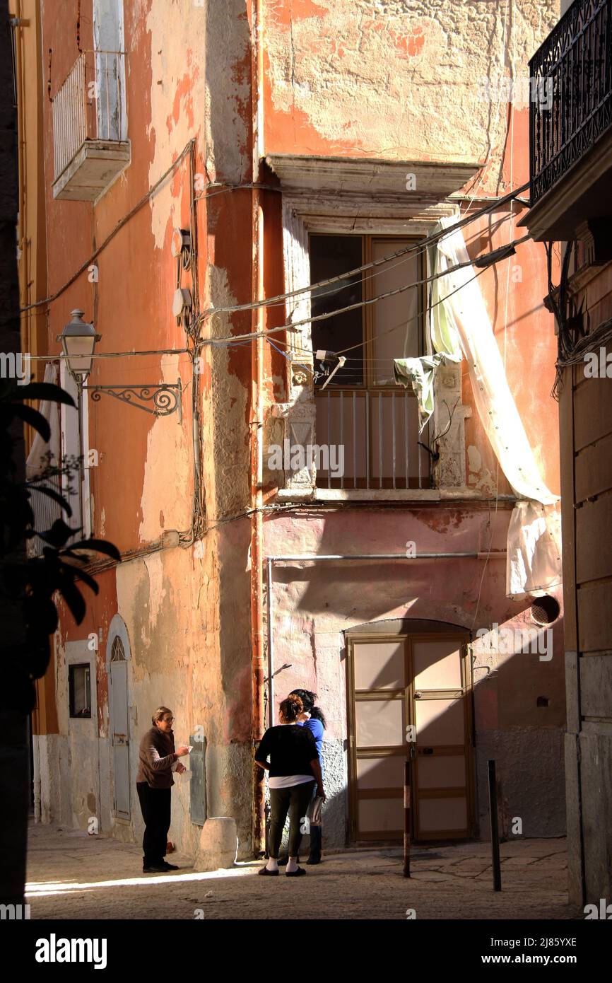 Bari, Italy. Local people talking outside an old, unkempt building in ...