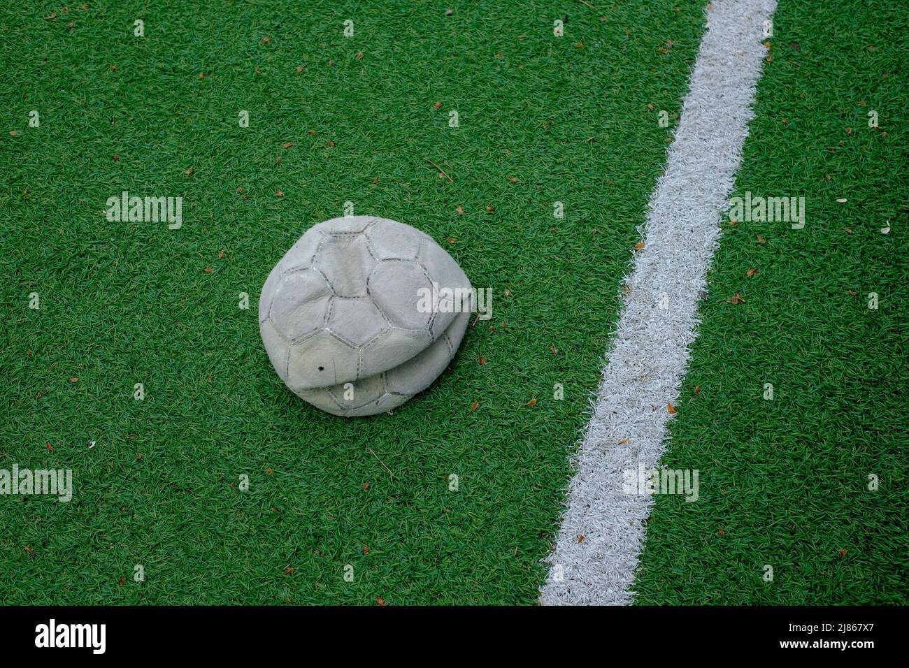 deflated soccer ball on green grass sport field. Impossible to play ...