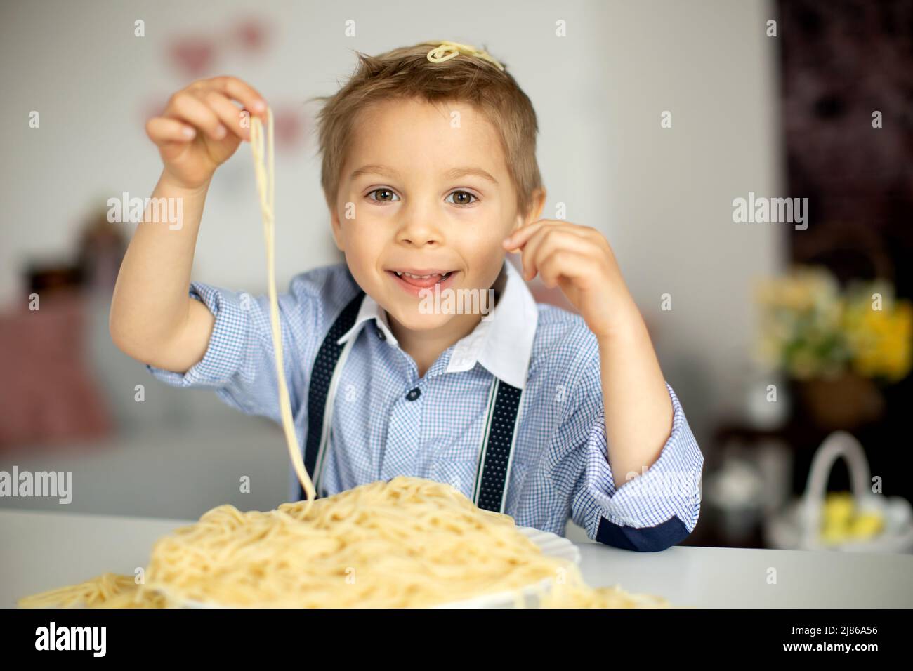 Cute preschool child, blond boy, eating spaghetti at home, making a ...