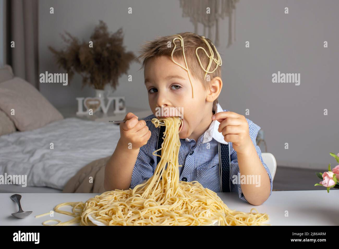Cute preschool child, blond boy, eating spaghetti at home, making a ...