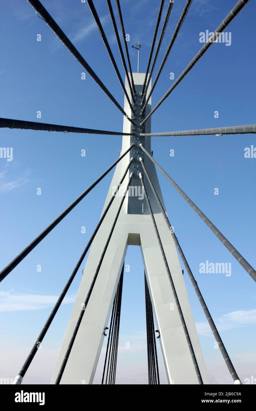 From below shot of bridge structure with wires on background of blue ...