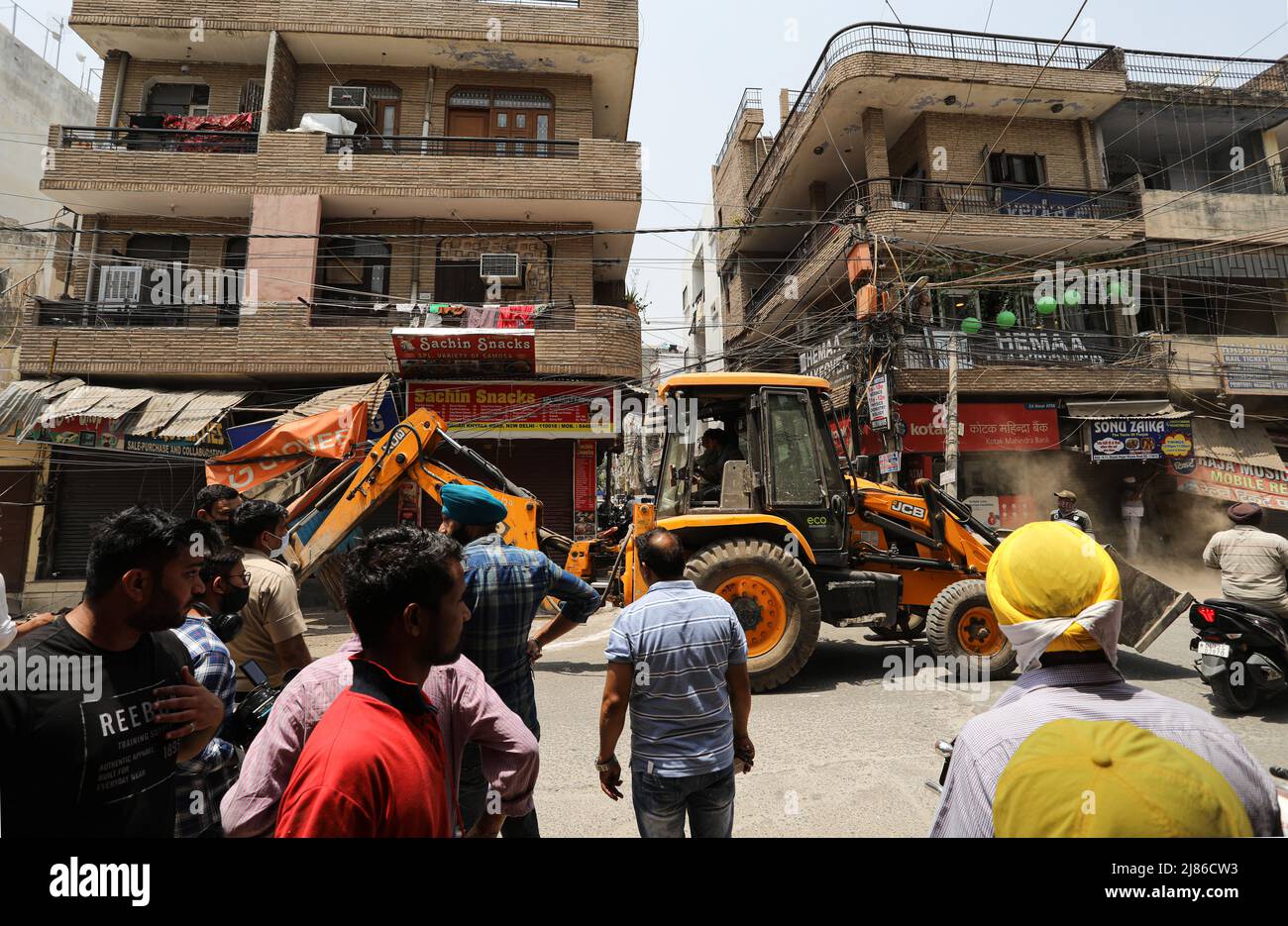 Residents look at a bulldozer demolishes illegal structure encroached ...