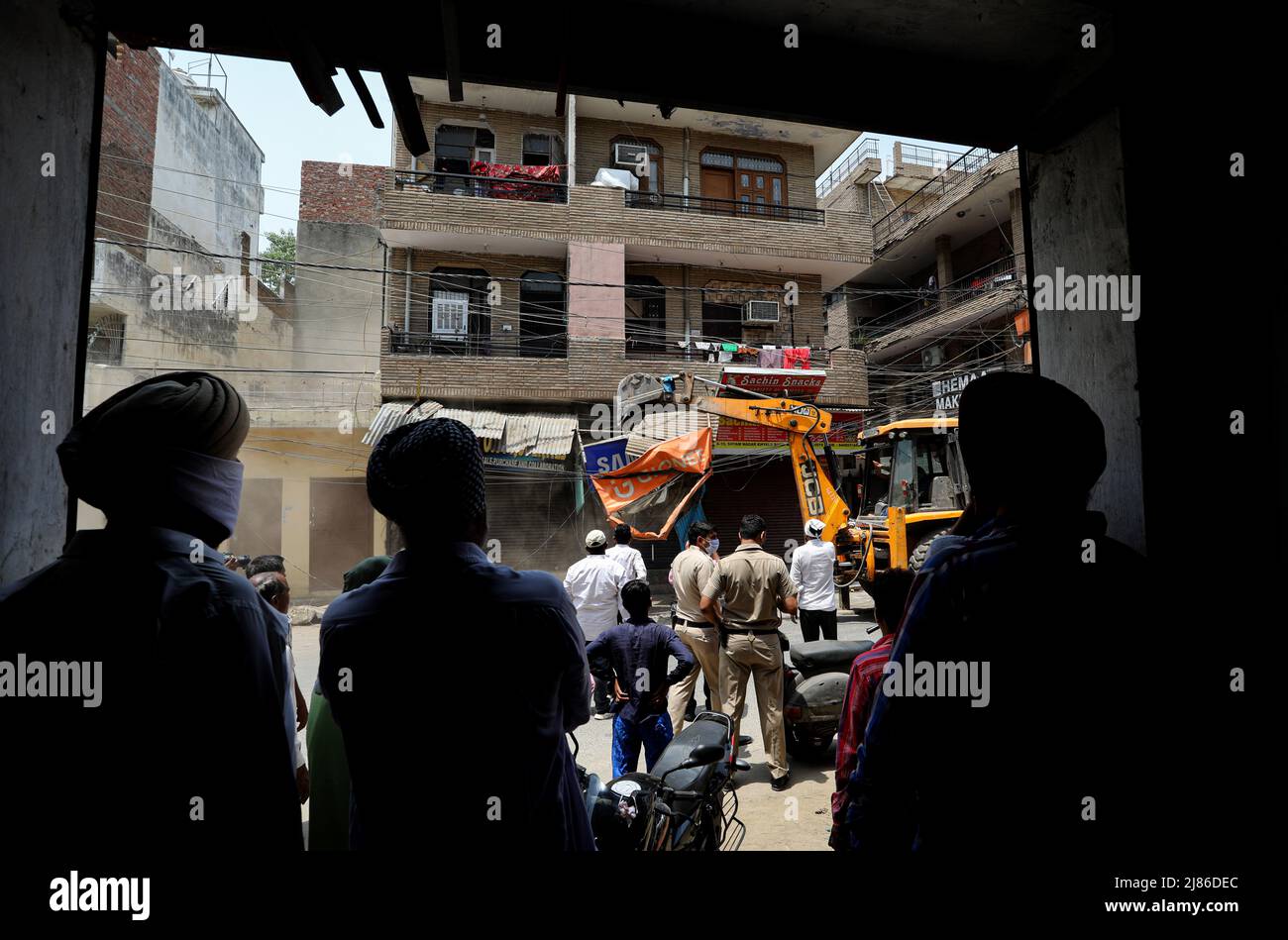 New Delhi, India - 13 May 2022, Residents look at a bulldozer ...
