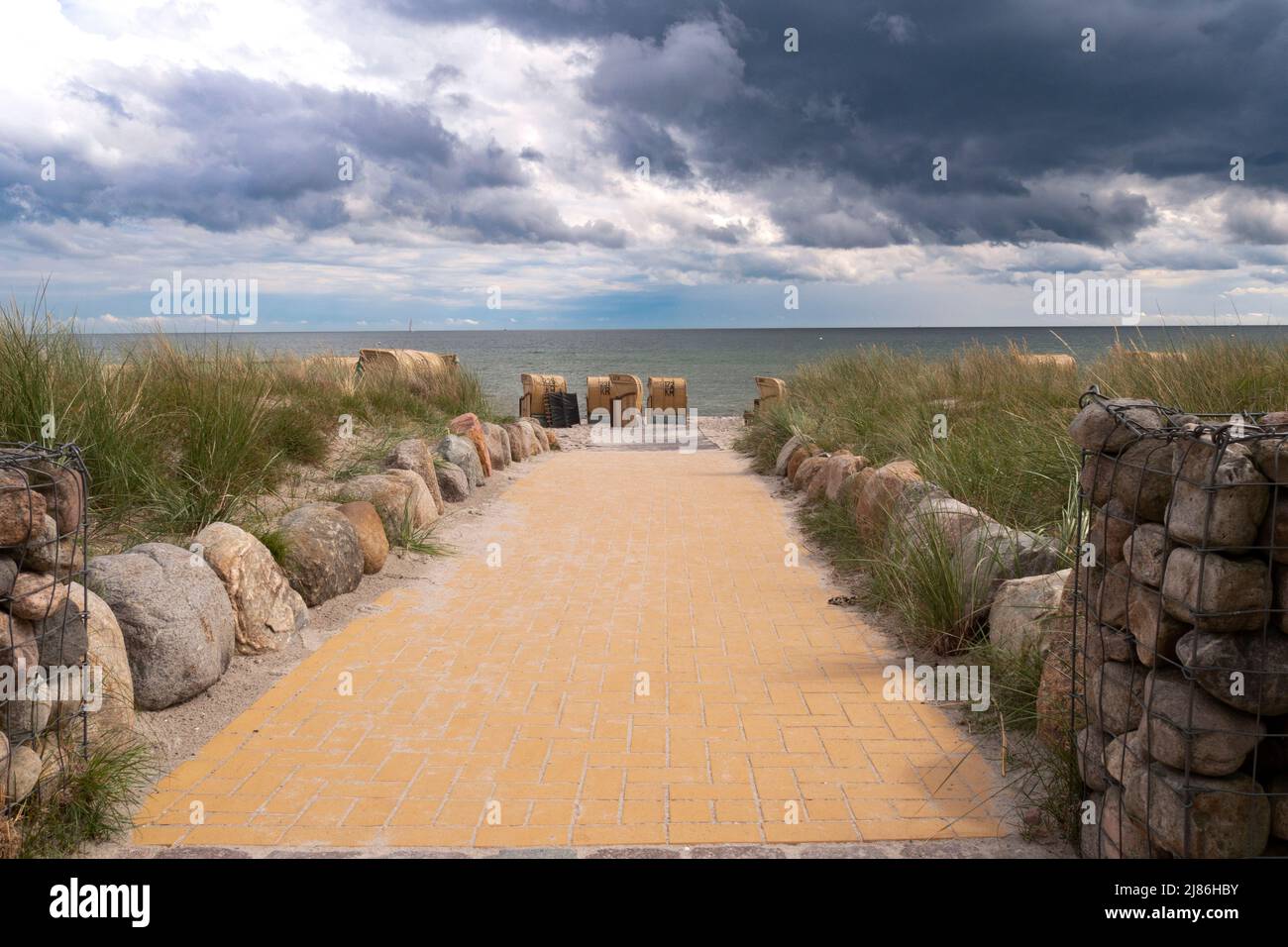 Beach access on the south beach on the island of Fehmarn in rain clouds ...