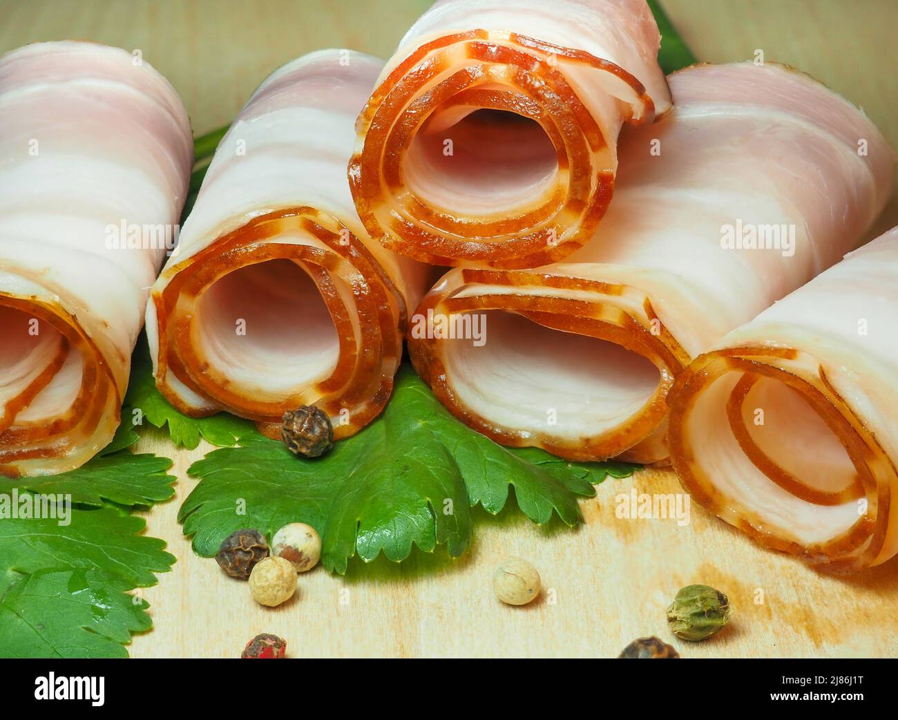 Curvy cut folded into rolls. Pork on a kitchen board with parsley ...