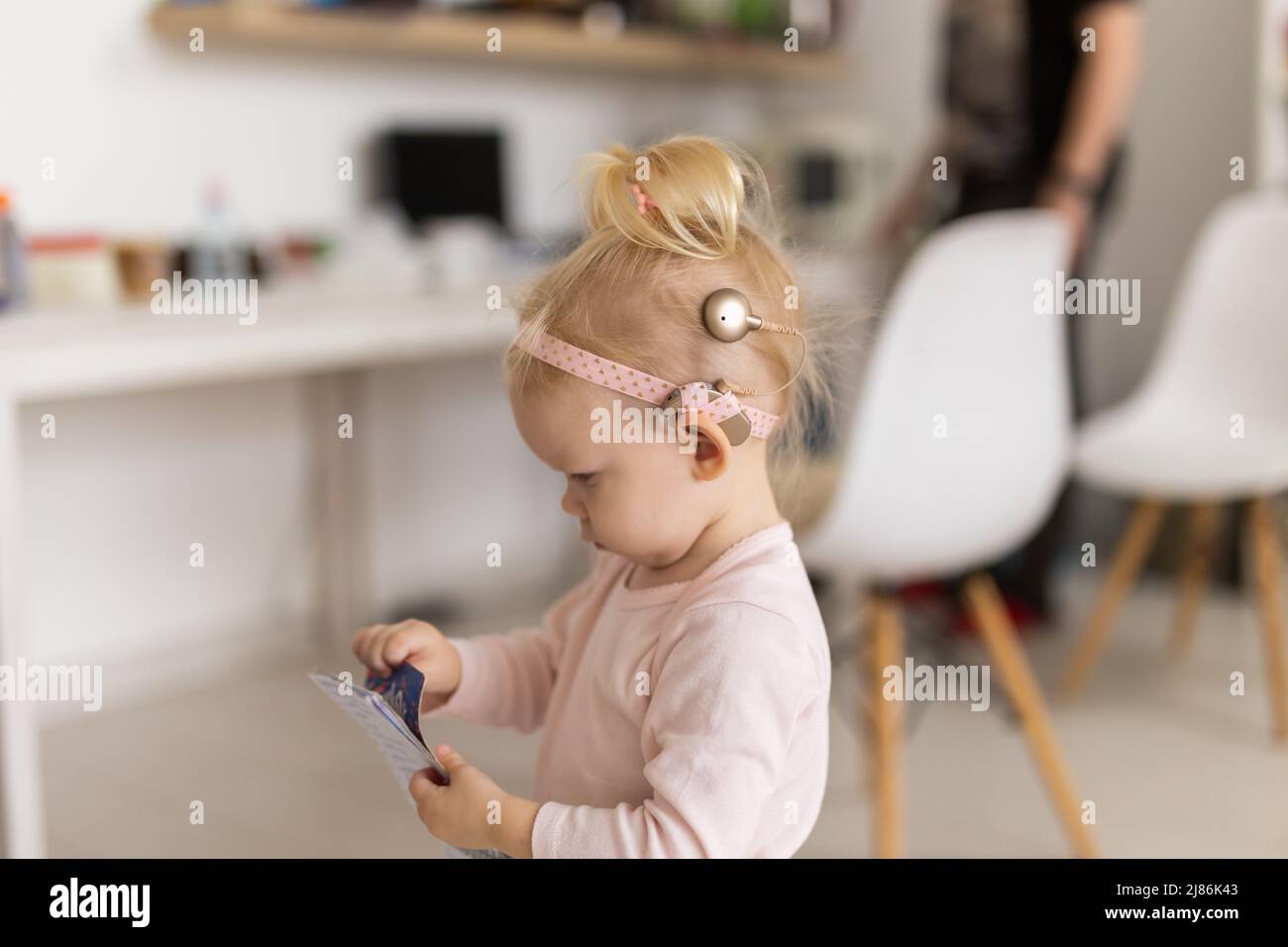 Baby with cochlear implants at home. Deafness and medical technology ...