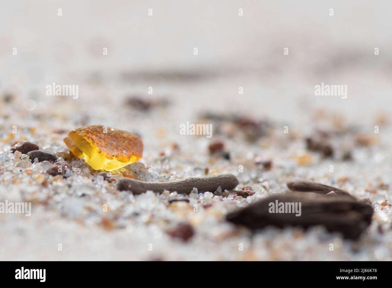 Beautiful piece of shining amber among the grains of sand and little ...