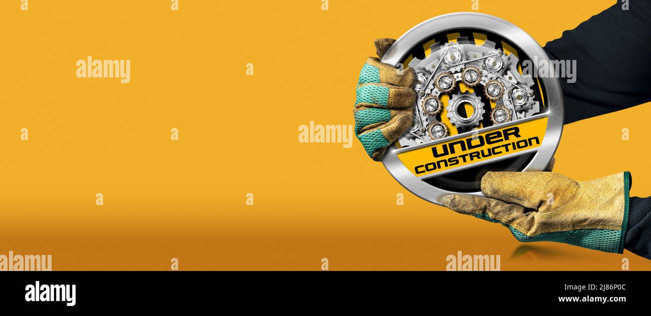 Manual worker with work gloves holding an under construction sign with ...