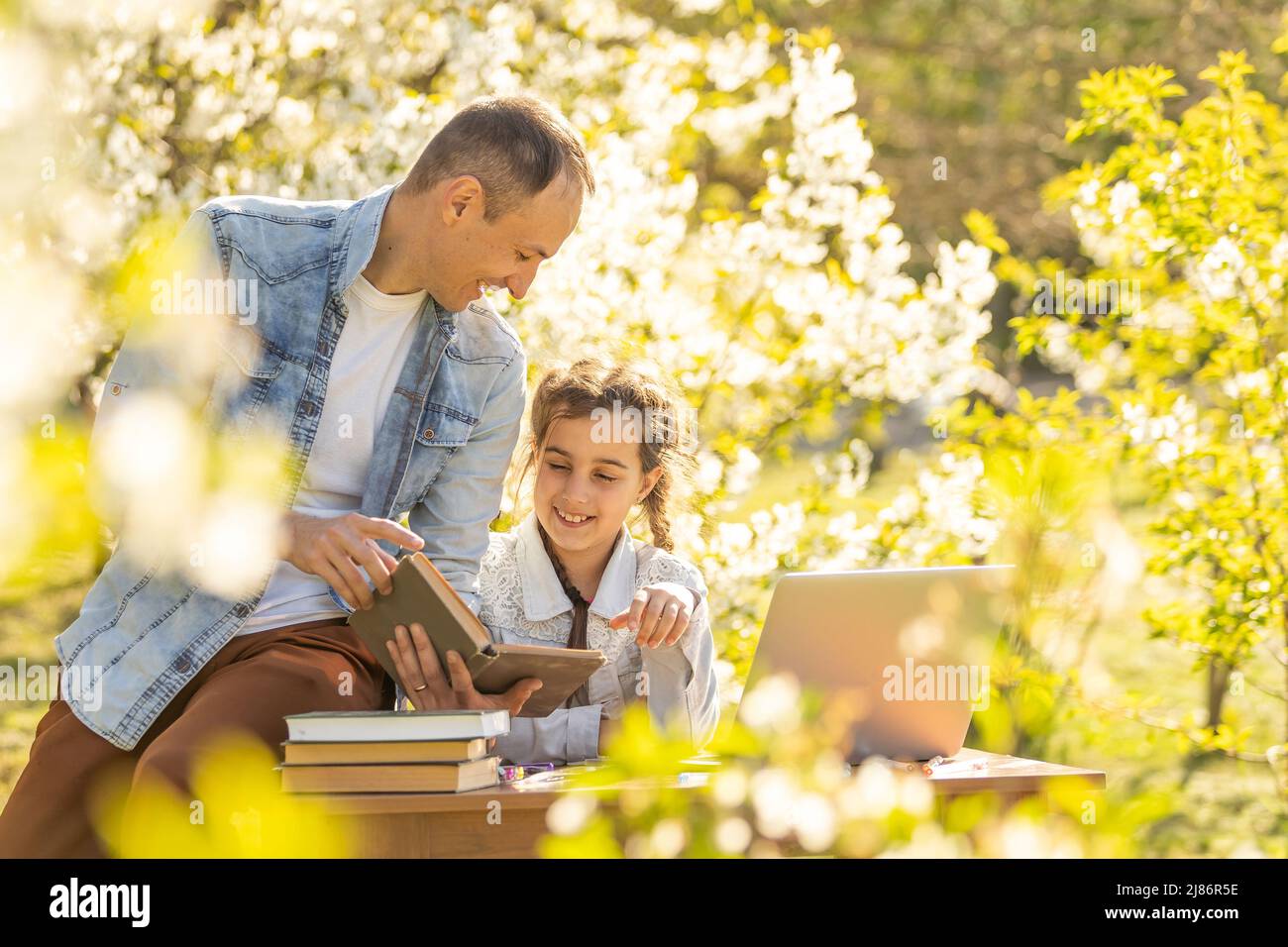 Caring young father helps little daughter, studying together watch ...