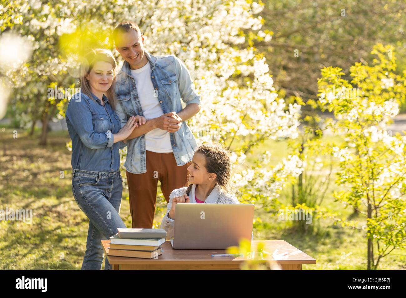Smiling young Caucasian family with small daughter look at laptop ...