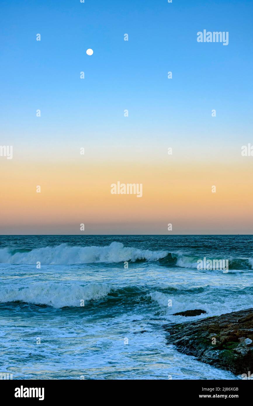 Moon over the sea and waves during sunset at Ipanema beach in Rio de ...