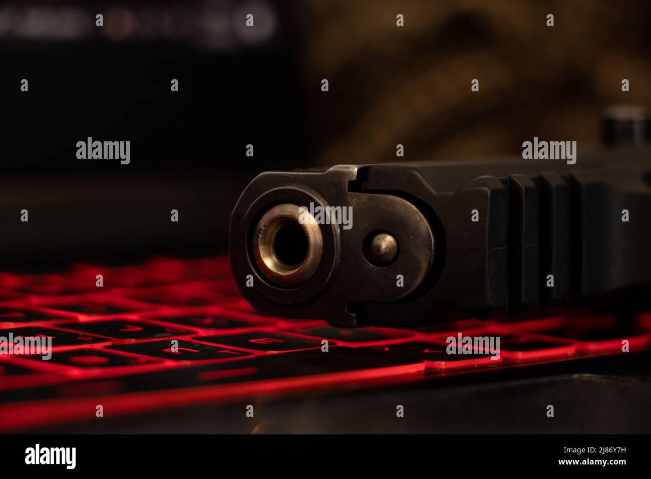 The gun lies on a black laptop keyboard with red backlight, security ...