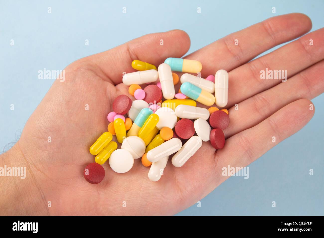 Man holding variety of medicine pills, capsules and tablets in his ...