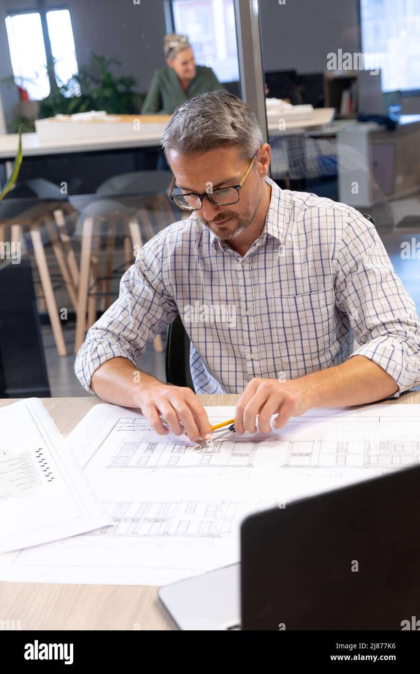 Confident caucasian male engineer drawing blueprint on paper at desk in ...