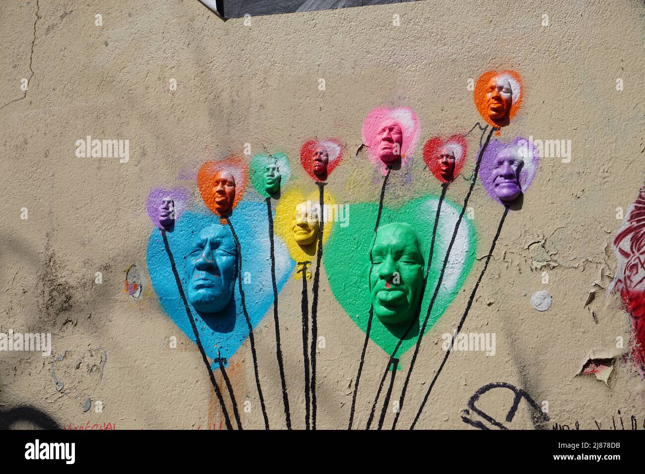 colorful sculpted, painted heads on a wall in Paris, France Stock Photo ...