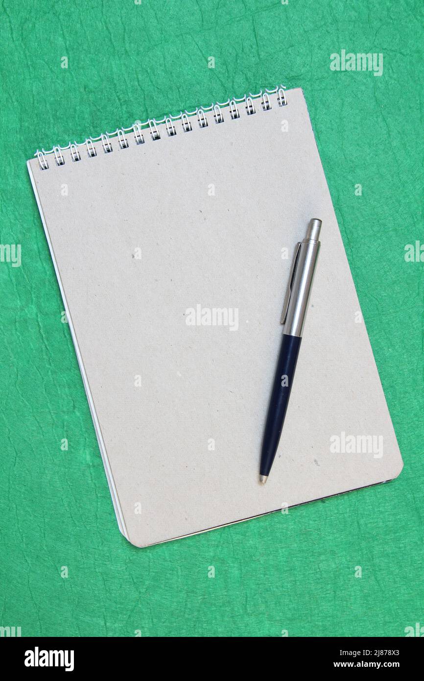 White and gray notepad sheet with spiral with pen against the ...