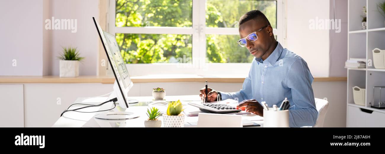 Businessperson Calculating Invoice With Computer On Desk Stock Photo ...