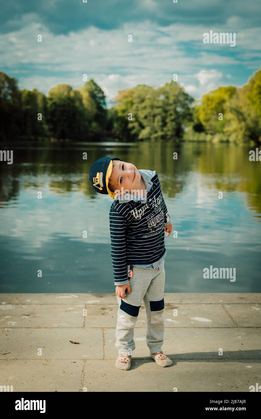 A small child stands near a lake in a park in the summer Stock Photo ...