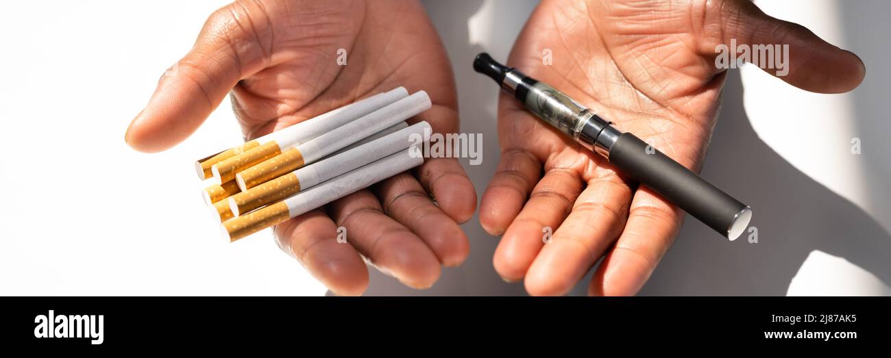 Man Holding Vape And Tobacco Cigarette Over Desk Stock Photo - Alamy