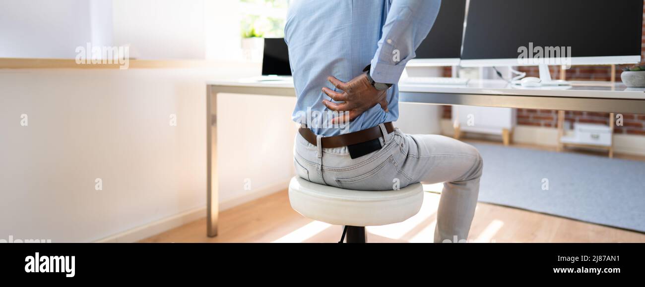 Young Businessman Having Back Pain While Sitting At Office Desk Stock ...