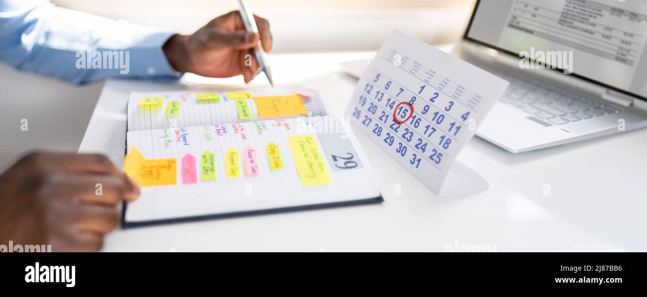 Businessman's Hand Checking Schedule In Diary With Calendar On White ...
