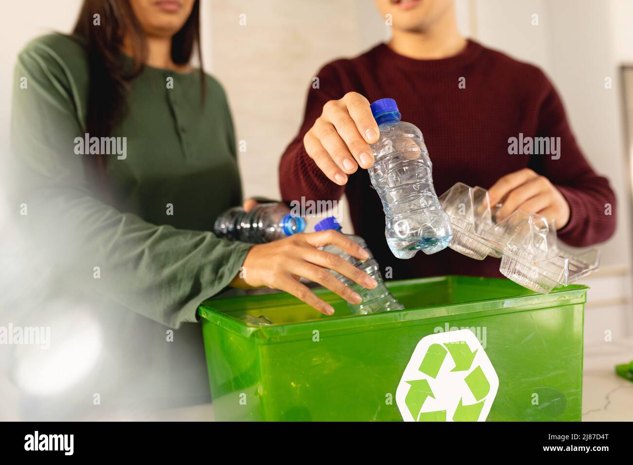 Midsection of asian young couple throwing plastic bottles in dustbin at ...