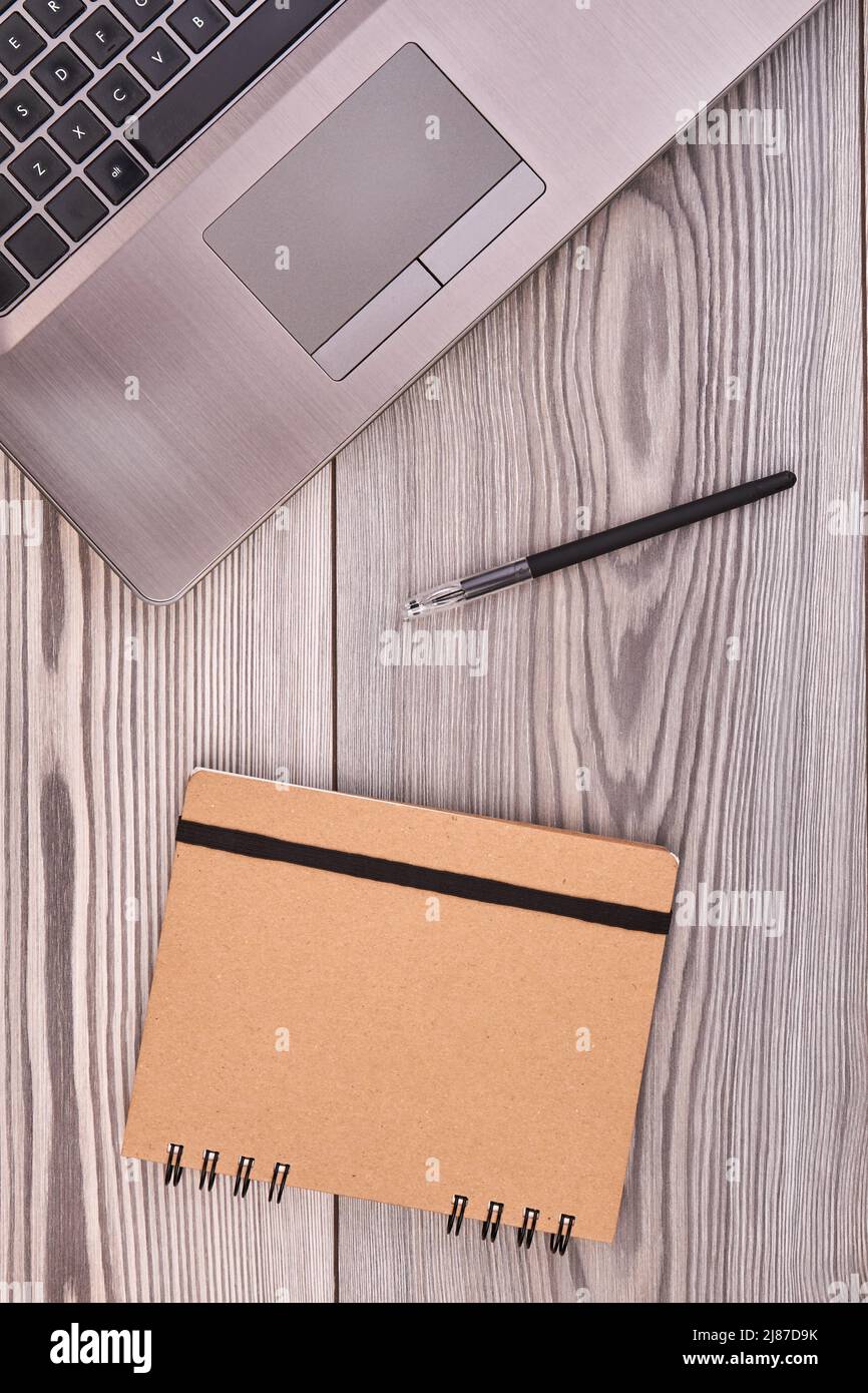 Office worspace desk with laptop and pen. Vertical shot beige notepad ...