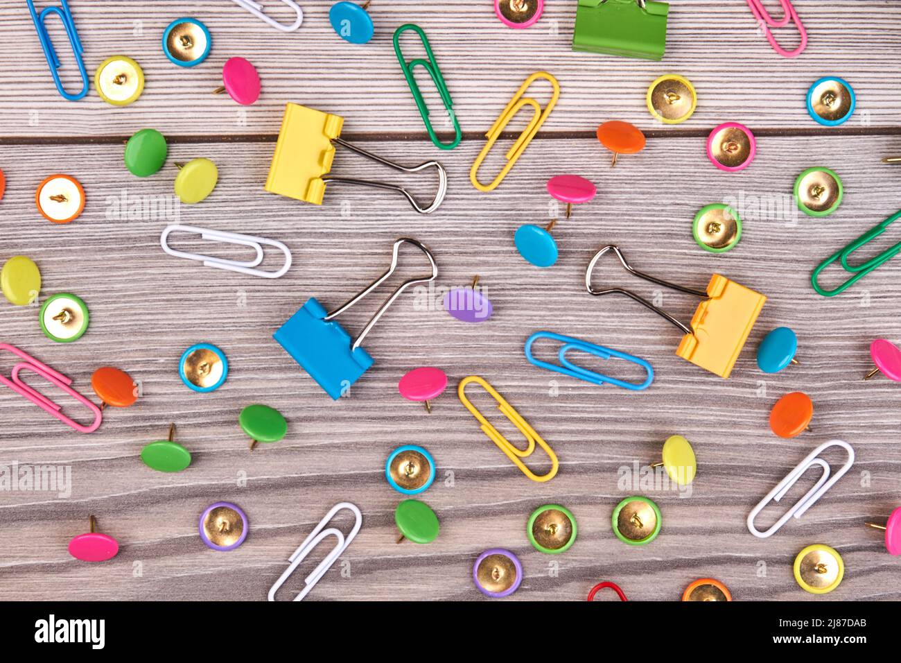 Collection of various type of paper clips on white wood. Set of ...