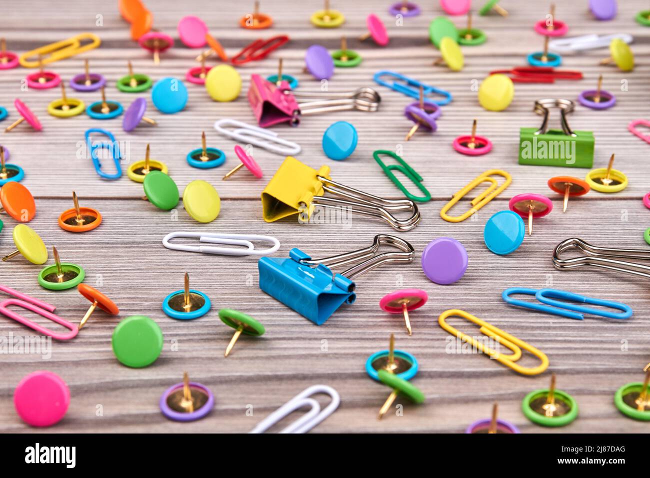 Set of various colorful paper clips on wooden desk. Many stationery ...