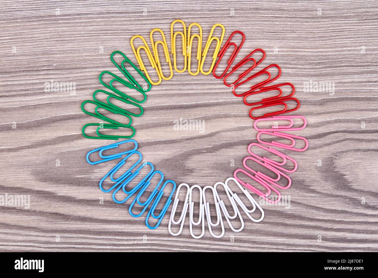 Top view colorful paperclips arranged in a circle. White desk ...