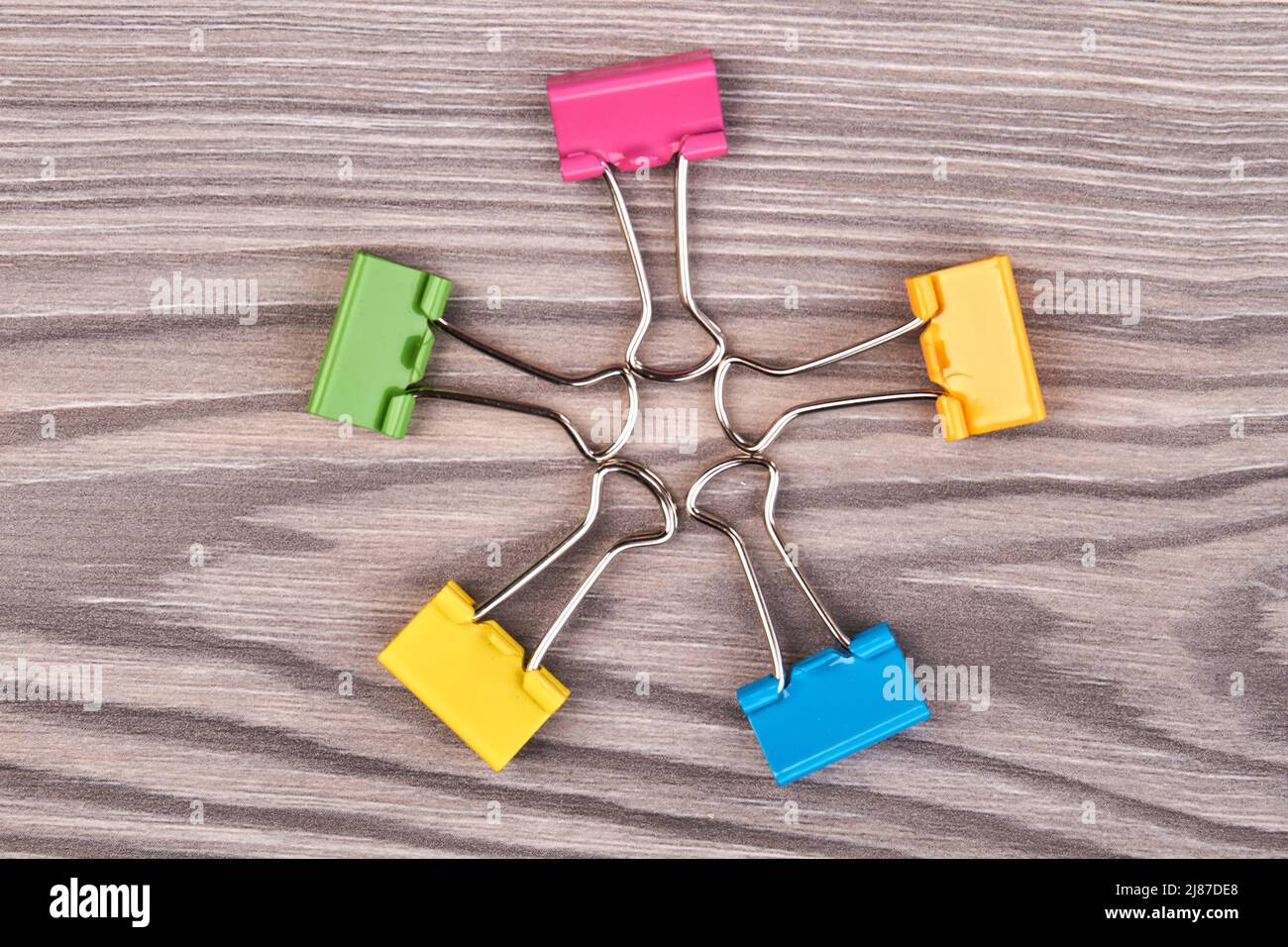 Top view five colorful binder clips on white wooden desk. Top view flat ...