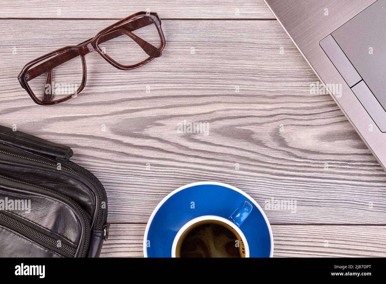 Top view office workdesk with cup of coffee and glasses. Grey wooden ...