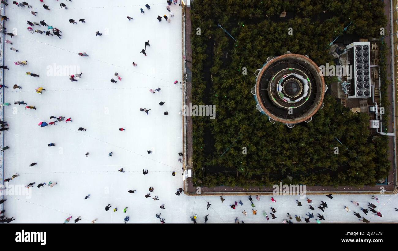 Aerial Drone View Over many people skating on an open-air ice rink in ...