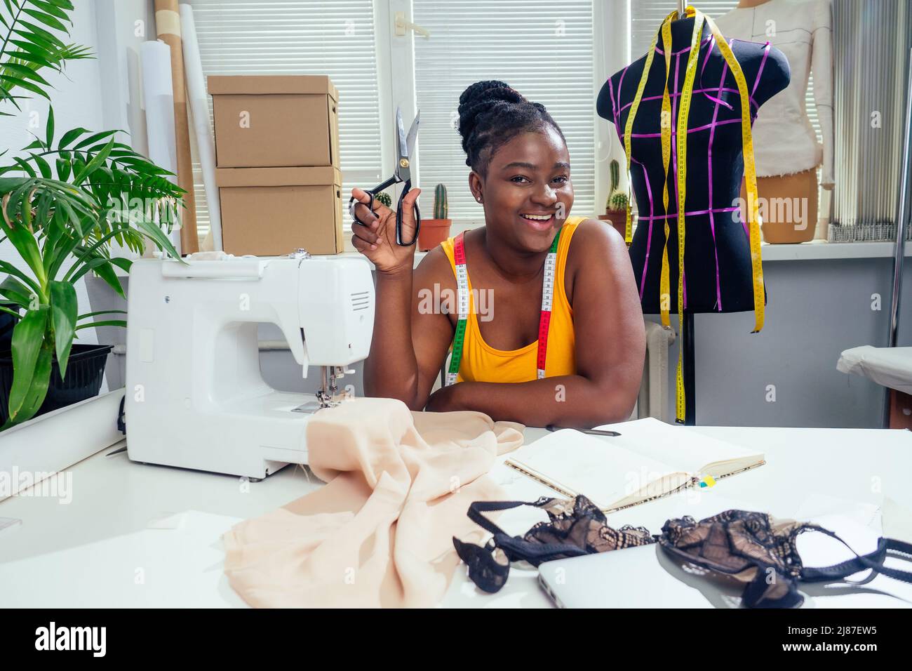 Young african american dressmaker woman sews clothes on sewing machine ...