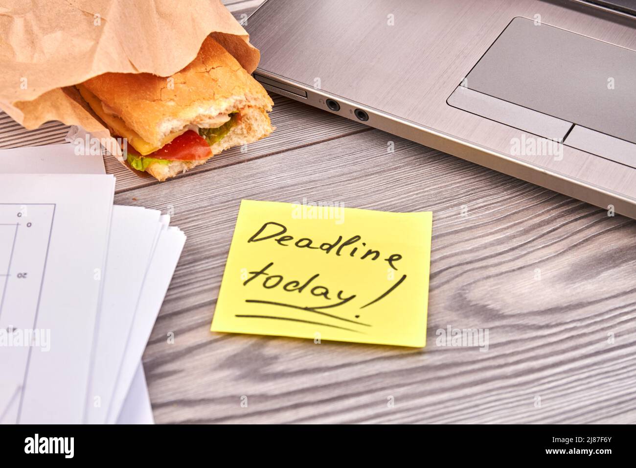 Sticky note with deadline today writing and baguette. White desk ...