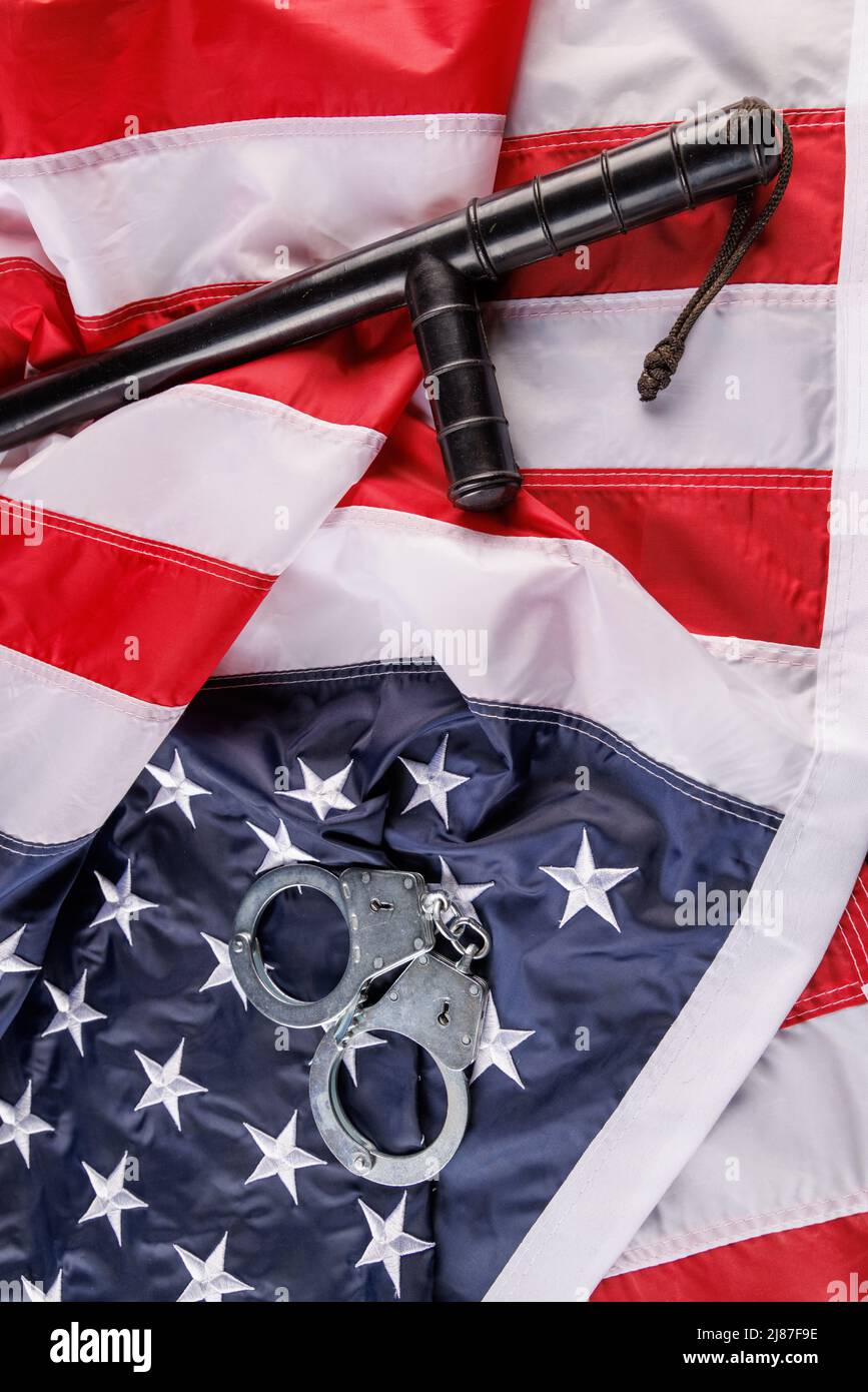 silver metal handcuffs and police nightstick over US flag on flat ...