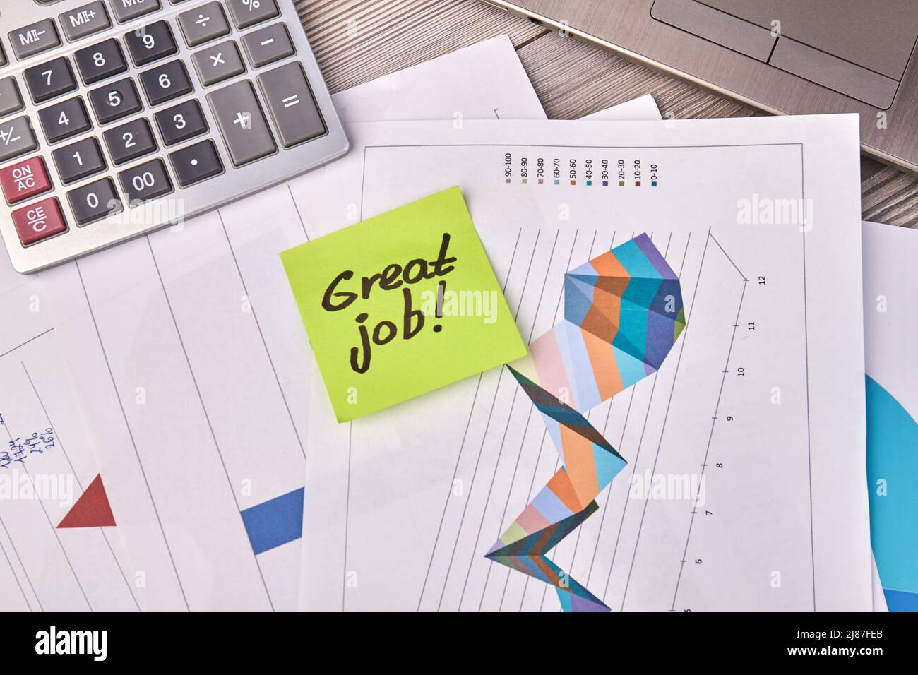 Sticky note with great job handwriting on papers with charts diagrams ...