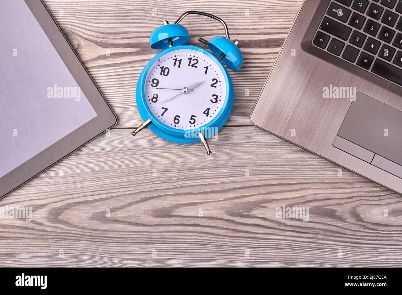 Blue alarm clock with laptop and tablet pc. White desk background Stock ...