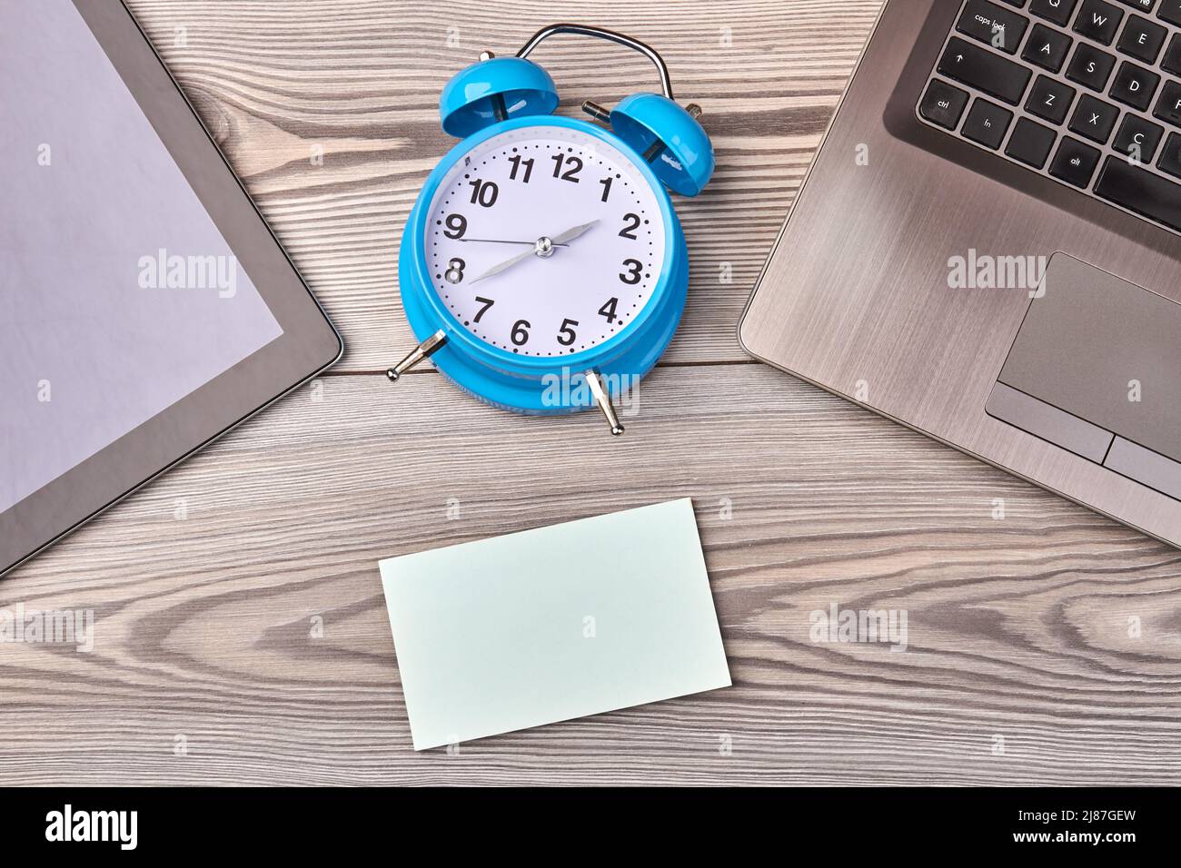 Alarm clock with blank paper for copy space on wooden desk. Top view ...