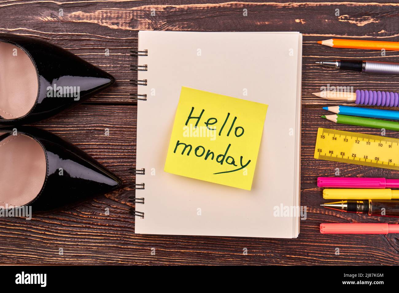 Top view pens with pencils and notepad. Sticky note with hello monday ...